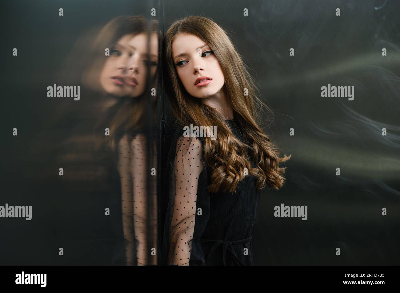 Portrait of a teenage girl leaning against a mirror surface. Girl in a ...