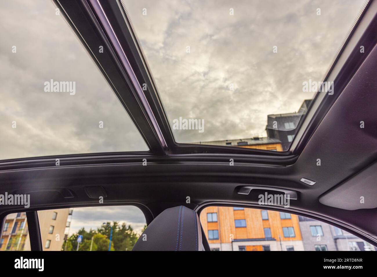 Close-up view of panoramic roof of car overlooking blue sky with white ...