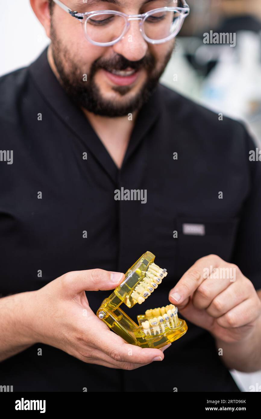 Positive doctor in black uniform explaining dental braces work showing ...