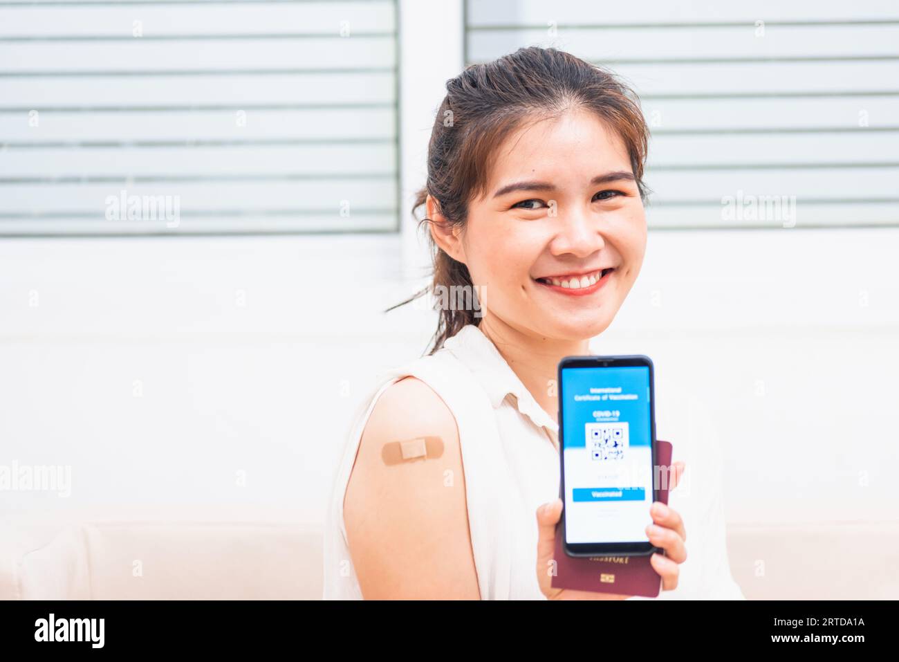 woman smile have adhesive plaster on arm her vaccinated and showing app ...