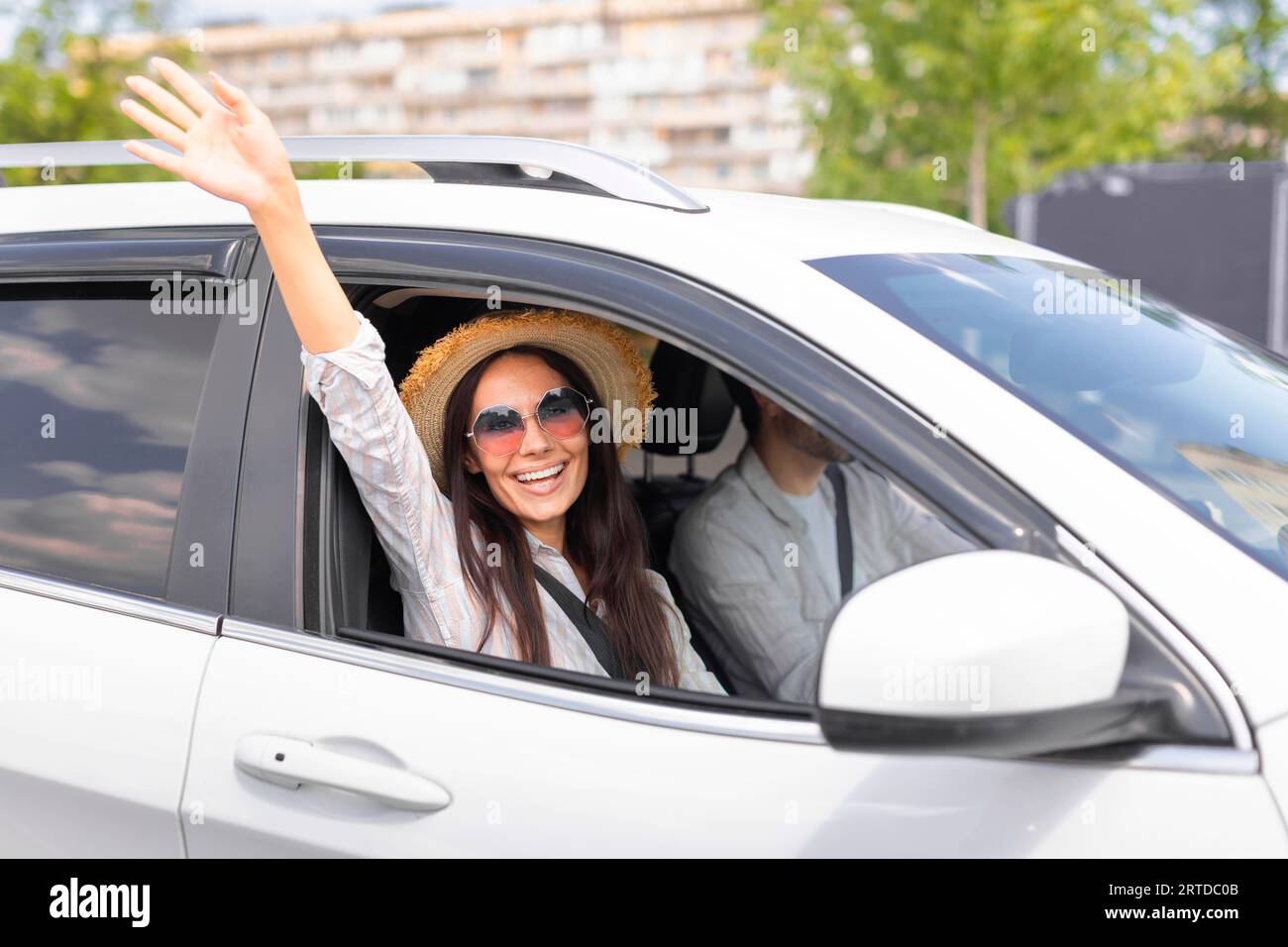 Carefree pretty lady waving from open car window Stock Photo - Alamy