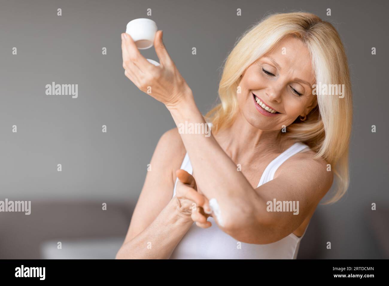 Body and skin care concept. Excited attractive mature woman applying ...