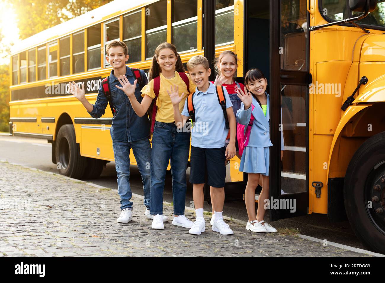Group Of Happy Children Standing Near School Bus And Waving At Camera ...
