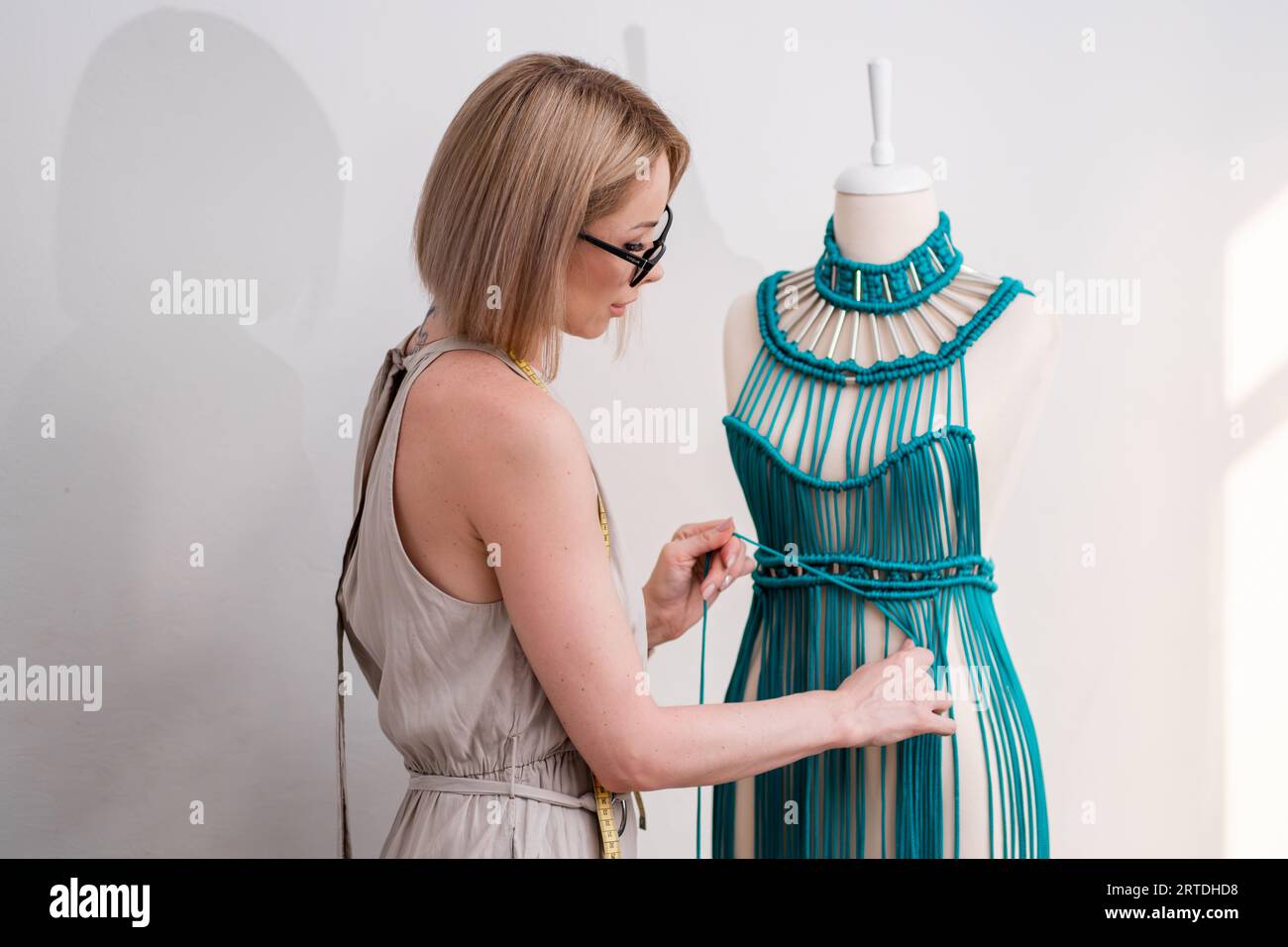 Craftswoman braids green threads making macrame dress in fashion ...