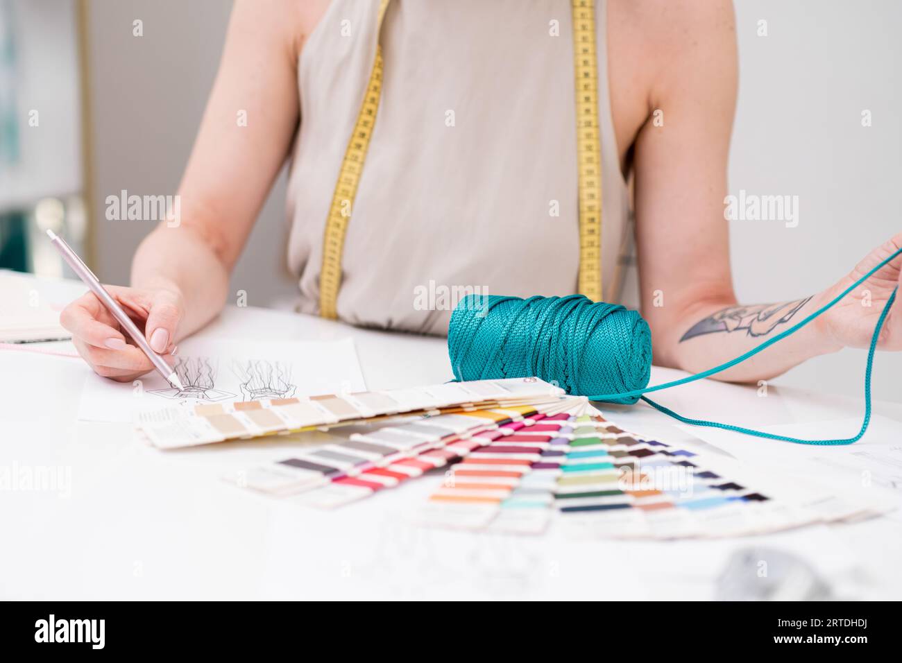 Dressmaker draws clothes holding green thread at workplace in fashion ...