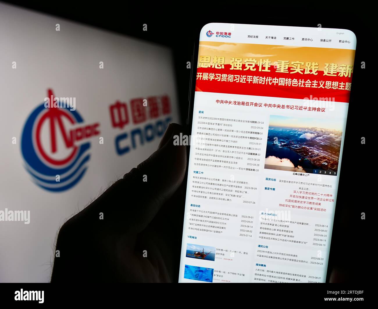 Person holding cellphone with website of China National Offshore Oil ...