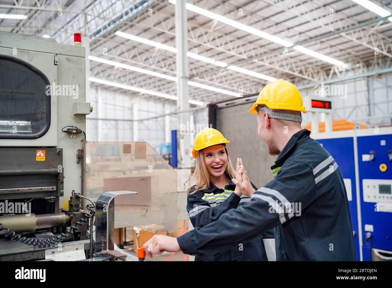 Industrial worker indoors in factory. Young technician with orange hard ...