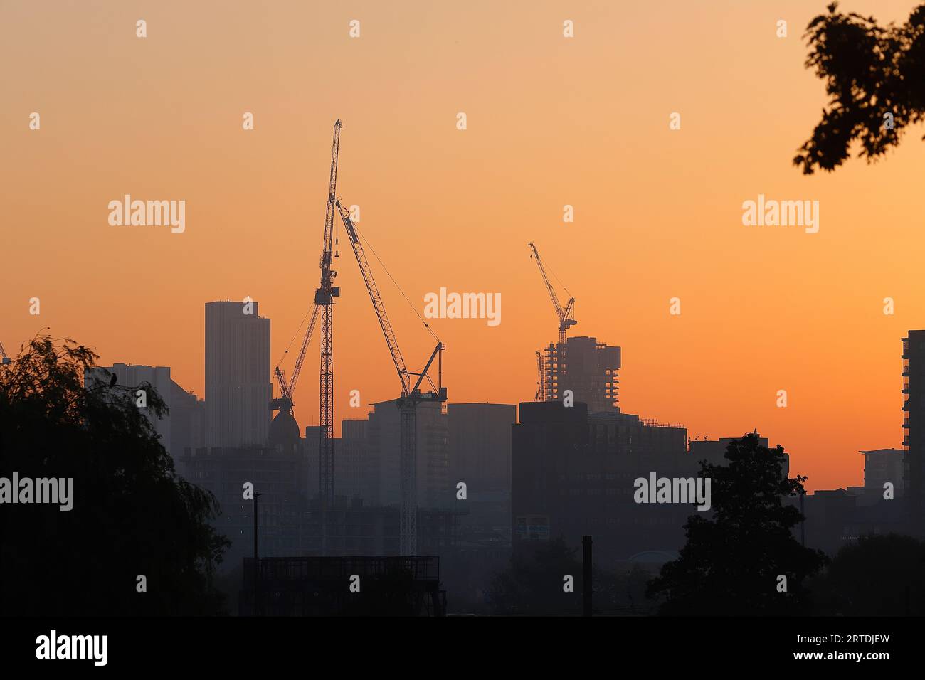 A view of Leeds City Centre at sunrise with tower cranes on various ...