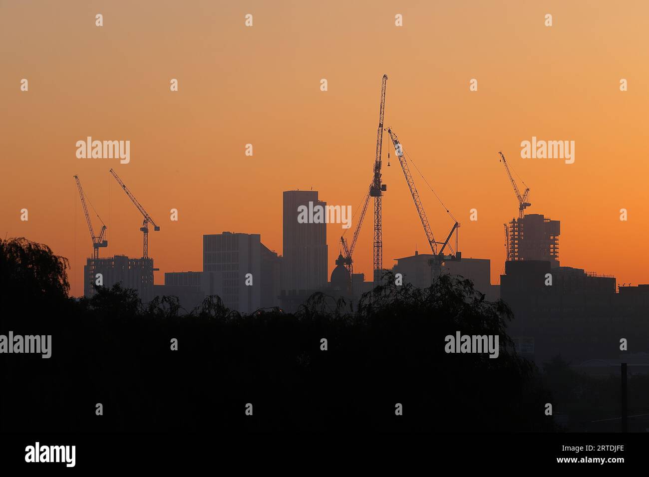 A view of Leeds City Centre at sunrise with tower cranes on various ...