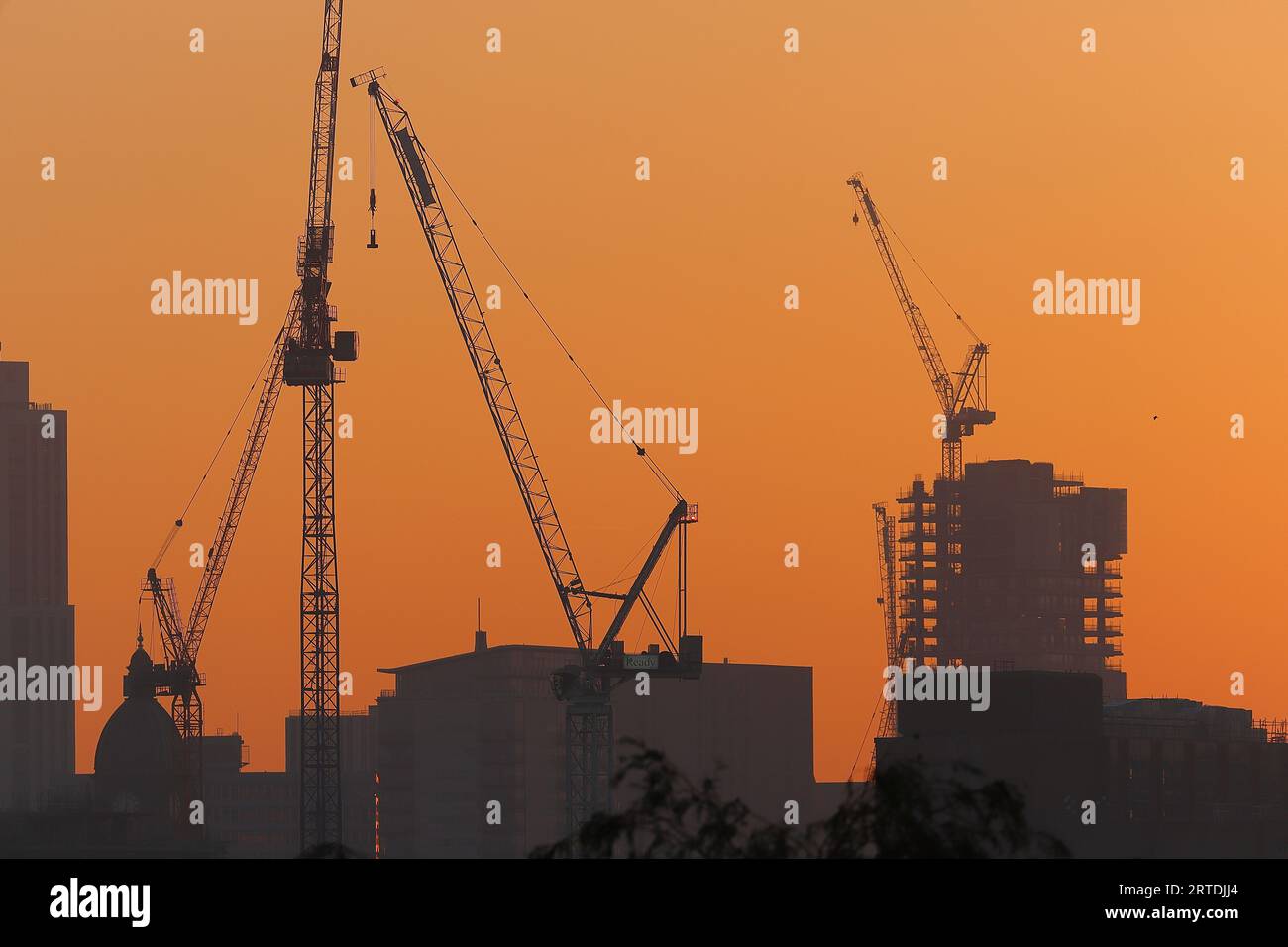 A view of Leeds City Centre at sunrise with tower cranes on various ...