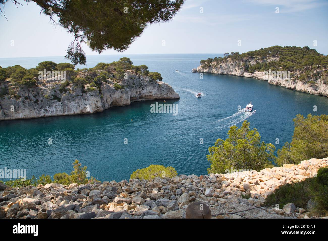 A boat in a calanque, green cliffs and red contrast. Blue water and sky ...