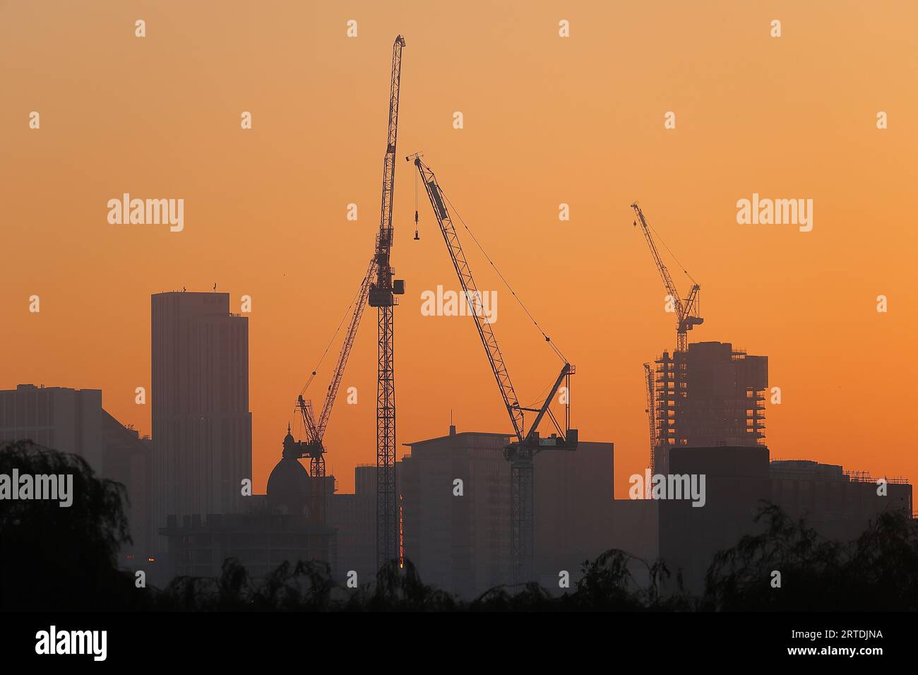 A view of Leeds City Centre at sunrise with tower cranes on various ...