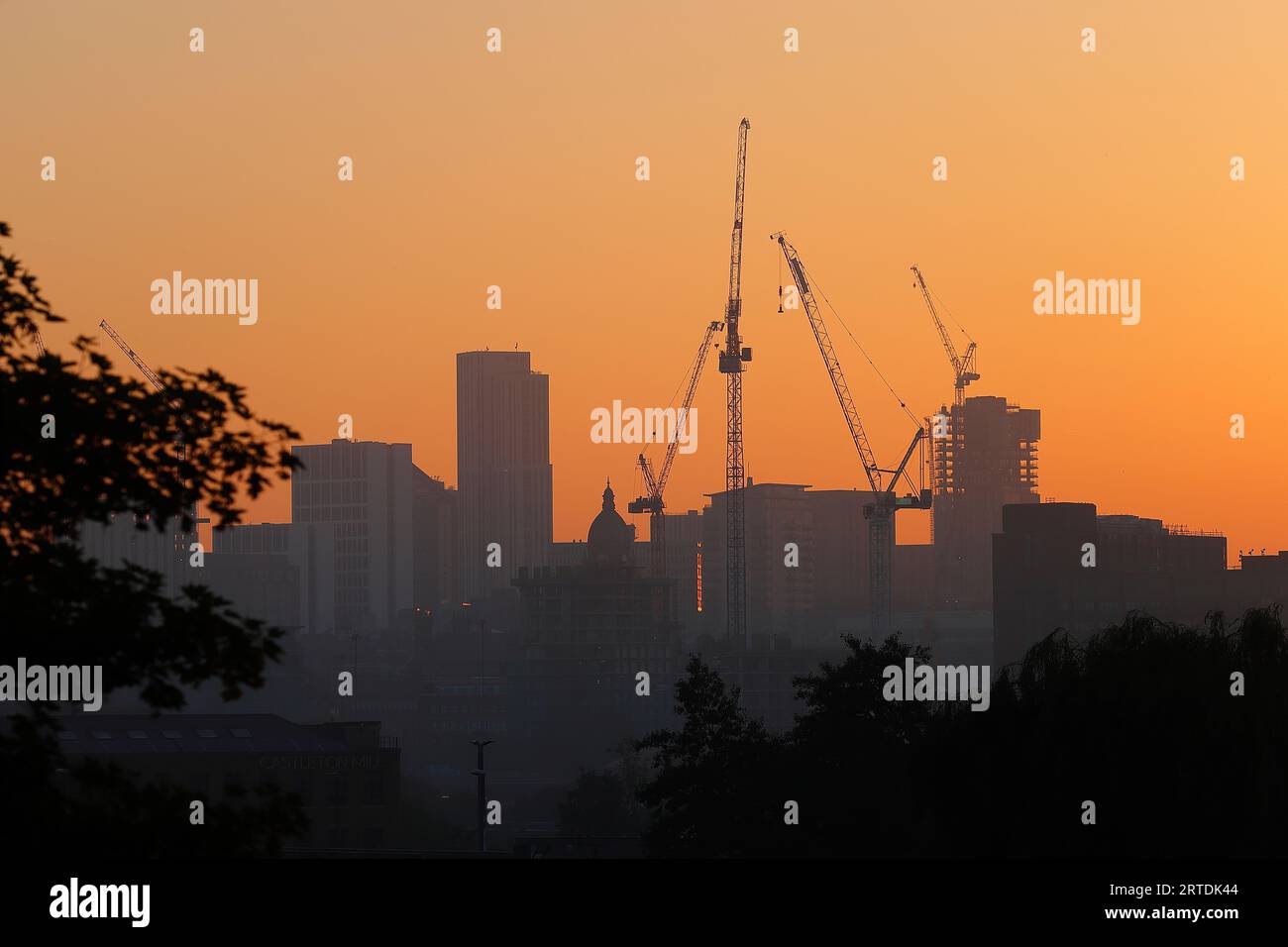 A view of Leeds City Centre at sunrise with tower cranes on various ...