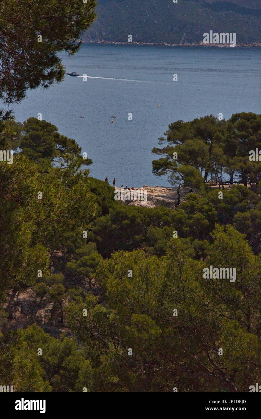 A boat in a calanque, green cliffs and red contrast. Blue water and sky ...