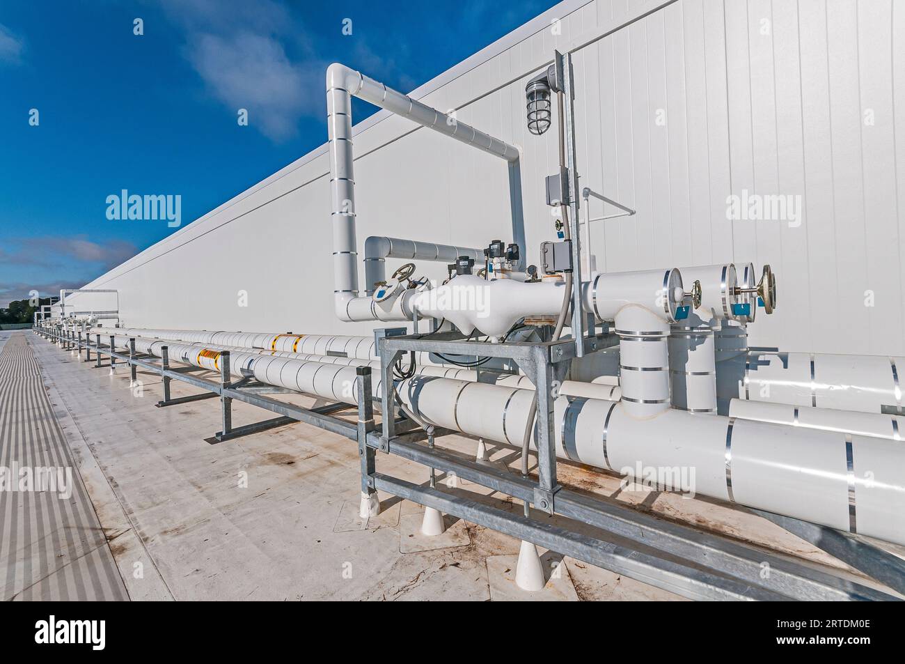 White insulated piping mounted on roof of cold storage facility, for ...