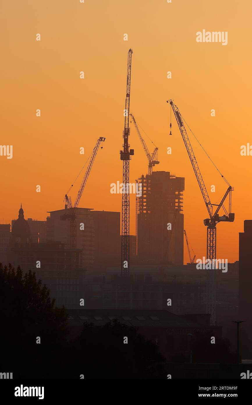 A view of Leeds City Centre at sunrise with tower cranes on various ...