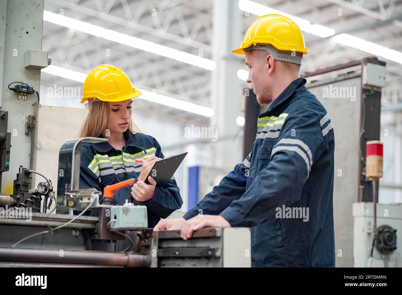 Industrial worker indoors in factory. Young technician with orange hard ...