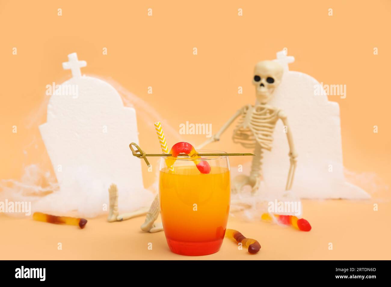Glass of delicious cocktail for Halloween with candies and skeleton on ...