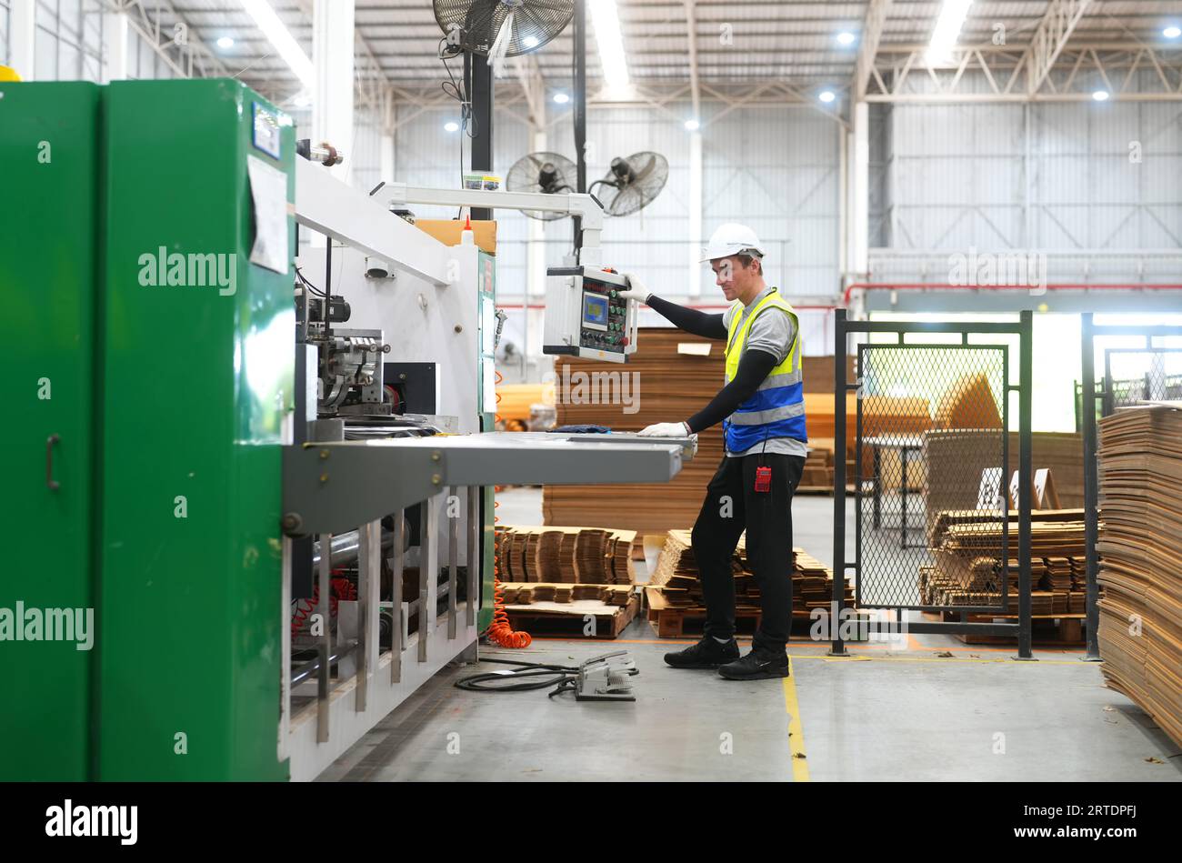 Industrial worker indoors in factory. Young technician with orange hard ...