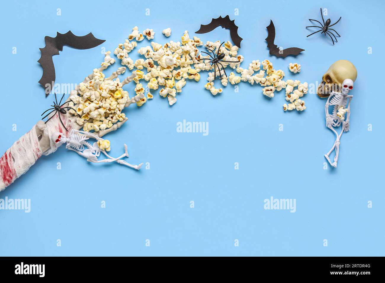 Composition with tasty popcorn, skeleton hand, skull and Halloween ...