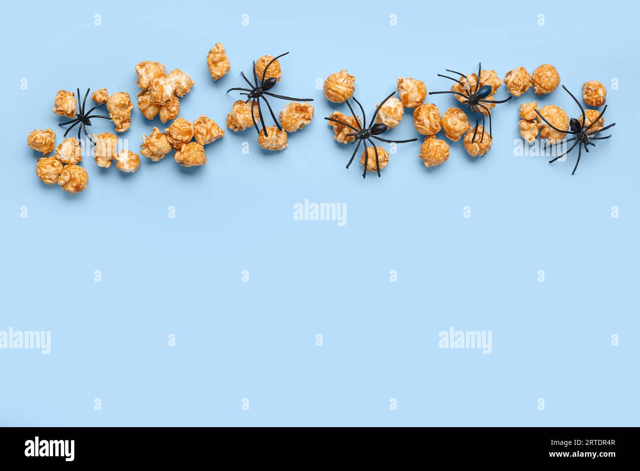 Composition with tasty caramel popcorn and spiders for Halloween ...