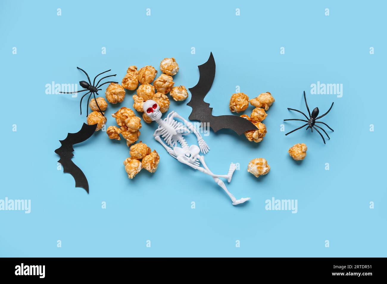 Composition with tasty caramel popcorn, paper bats, skeleton and ...