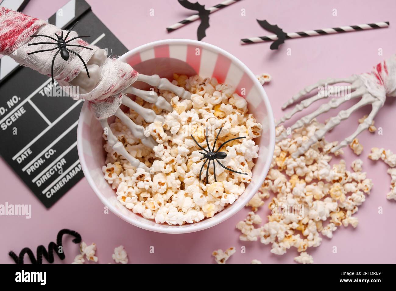 Bucket with tasty popcorn, skeleton hands and clapperboard for ...