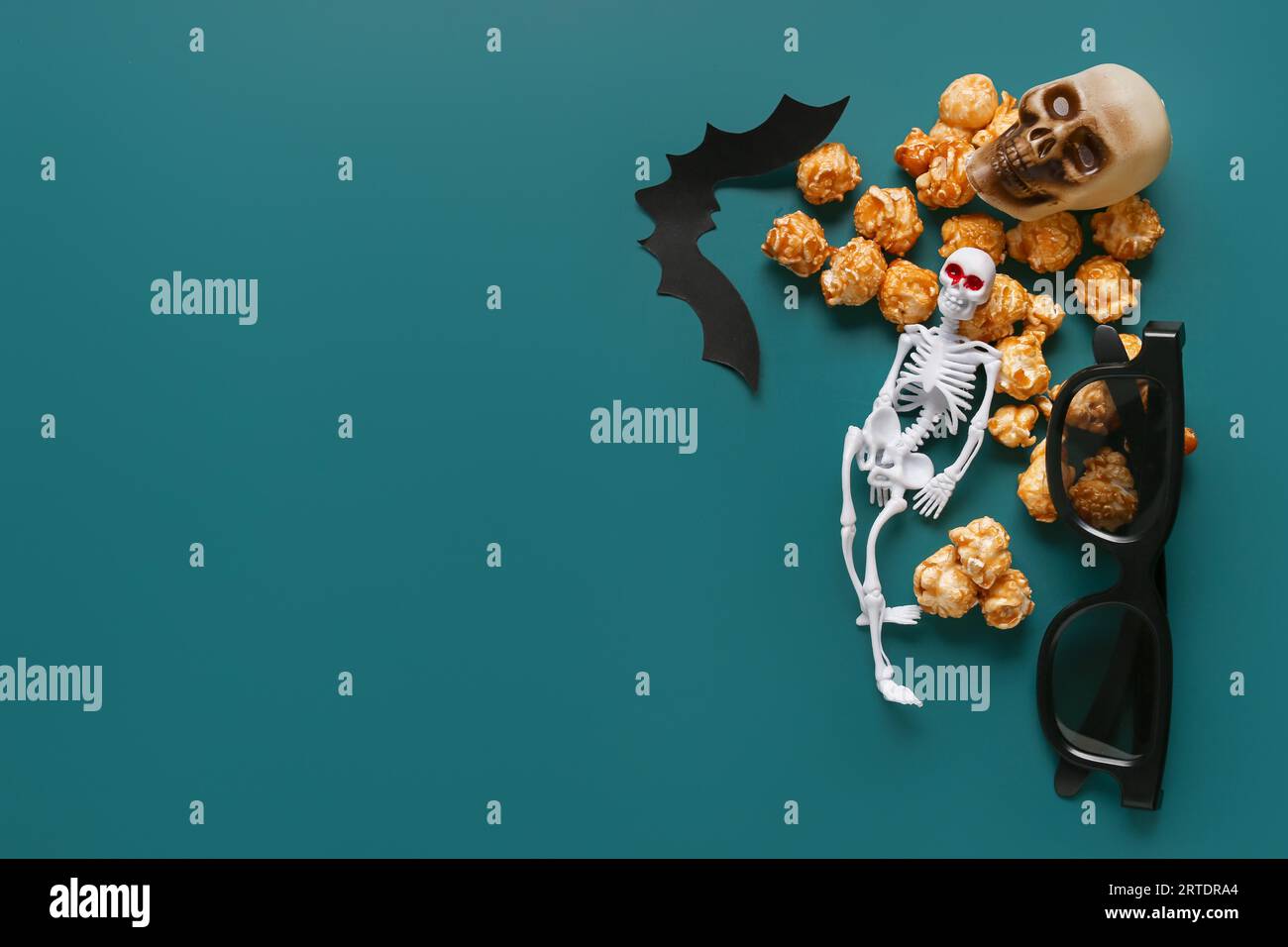 Composition with tasty caramel popcorn, skeleton, skull and 3D glasses ...