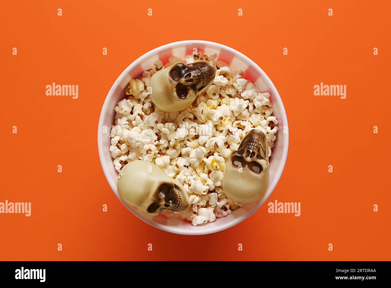 Bucket with tasty popcorn and skulls for Halloween celebration on ...