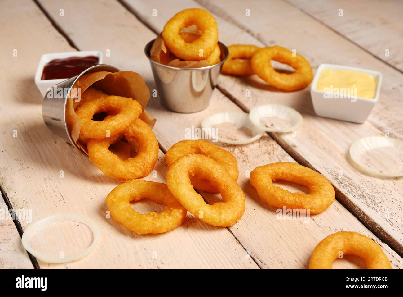 Metal buckets with fried breaded onion rings and different sauces on ...