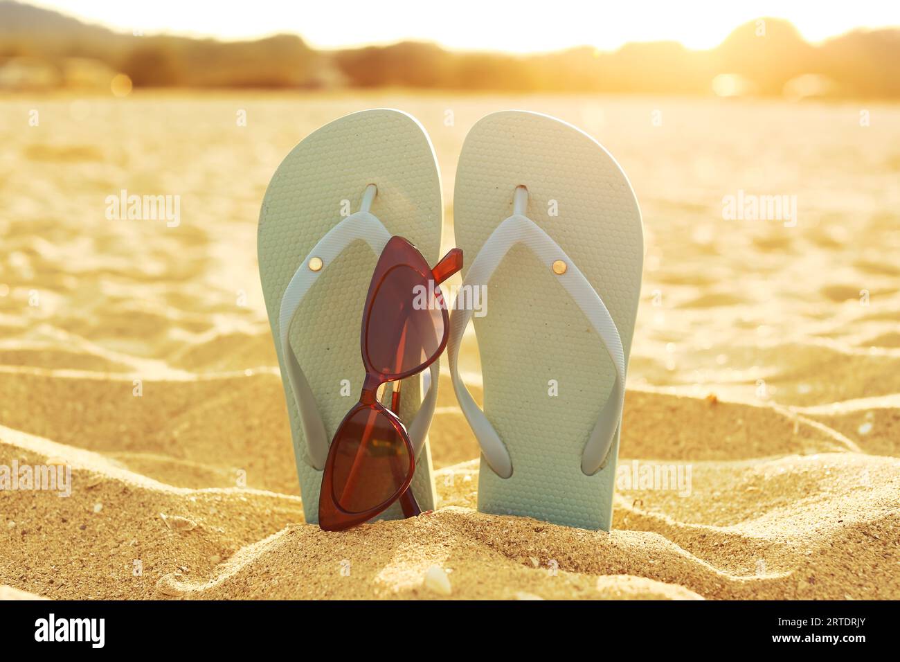 Stylish brown sunglasses and flip flops on sand Stock Photo - Alamy