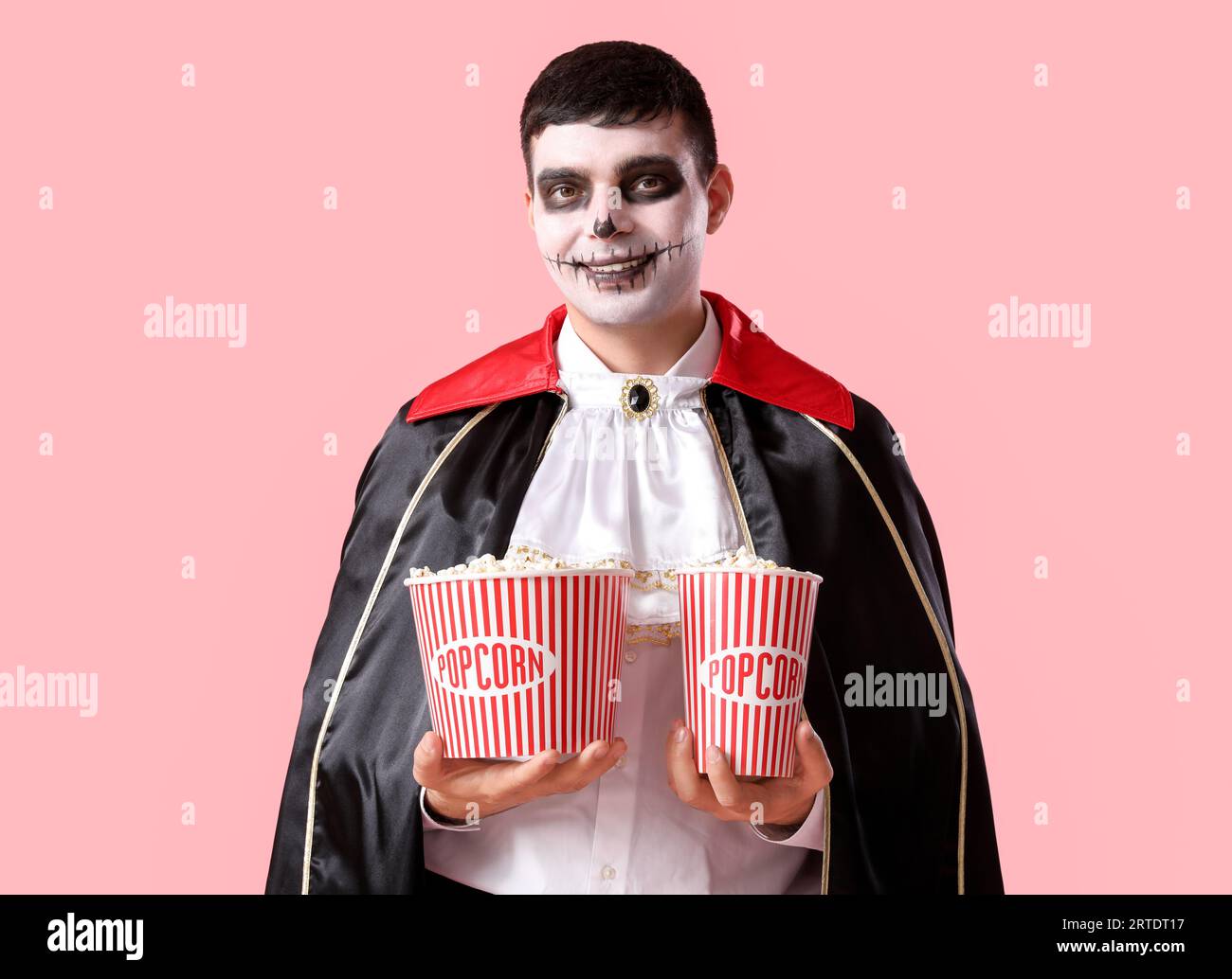 Young man dressed for Halloween as vampire with popcorn on pink ...