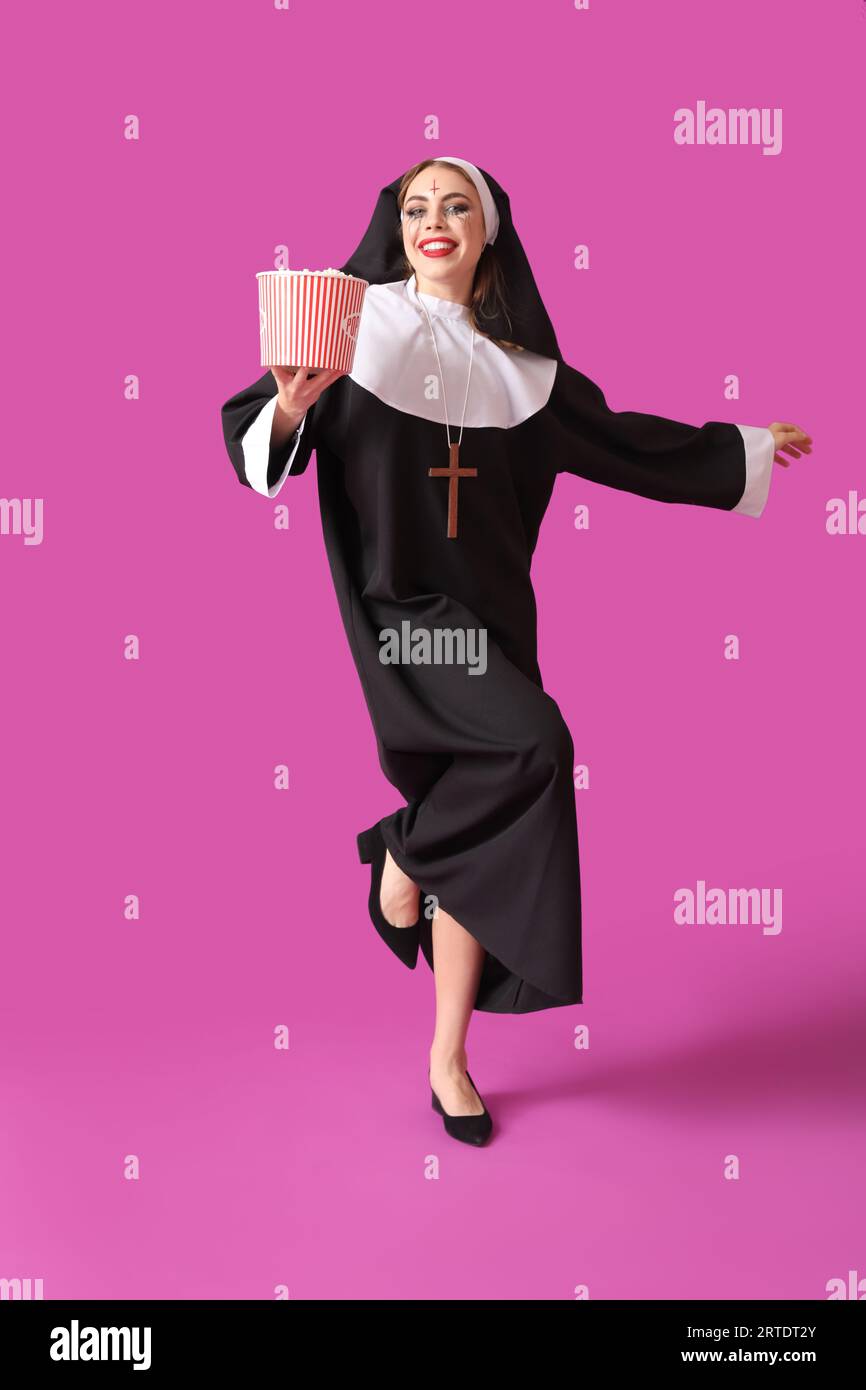 Young woman dressed for Halloween as nun with popcorn on color ...