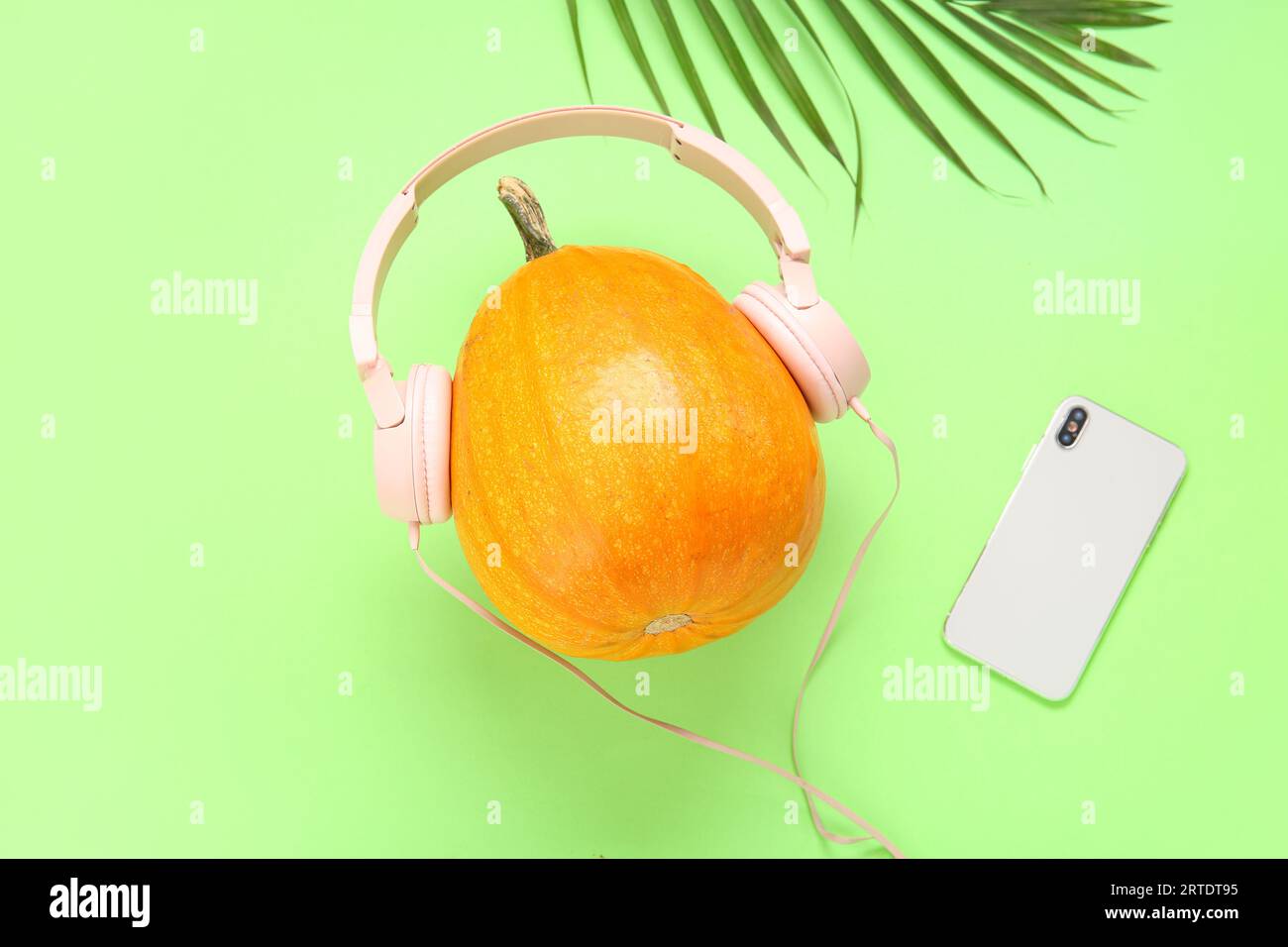 Halloween pumpkin with modern headphones and mobile phone on green ...