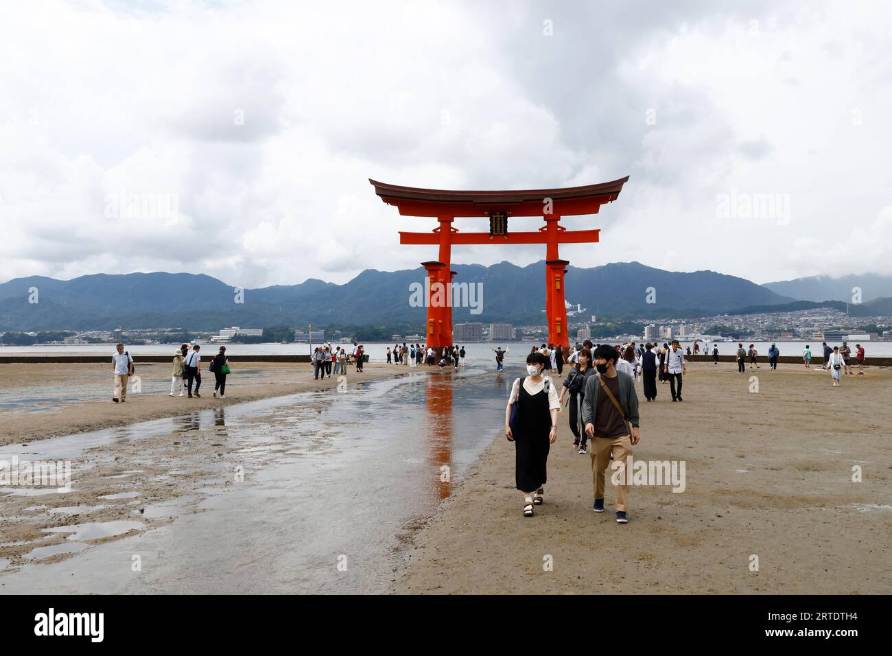 Tourists pose in front of a giant "torii" gateway at Itsukushima Shrine ...