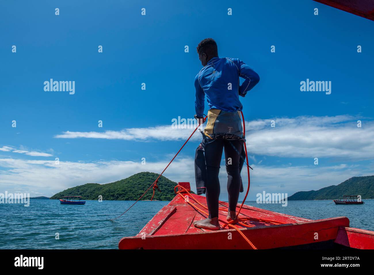 Cape Maclear, Malawi. A man pulls in the anchor on a scuba diving boat ...