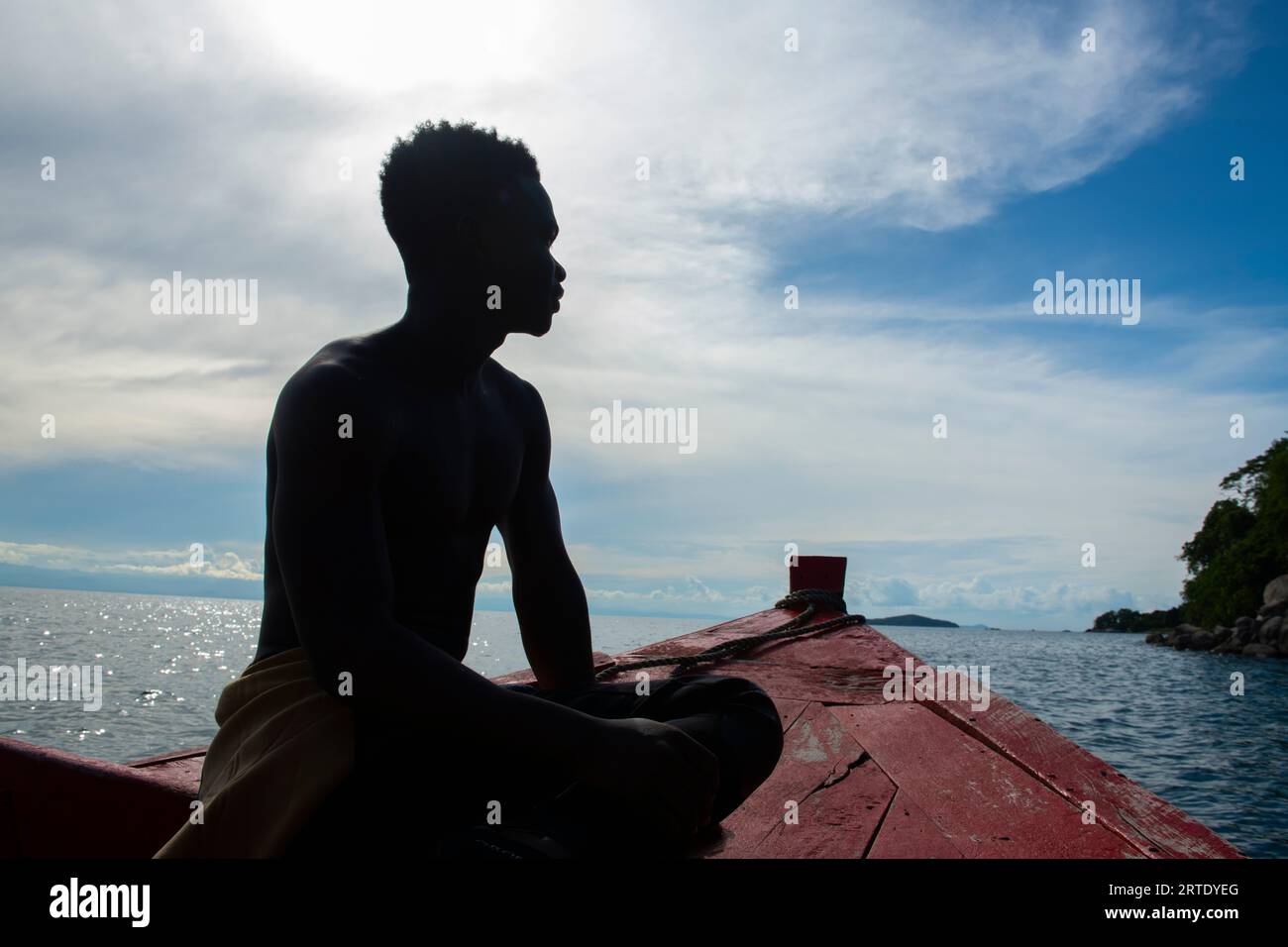 Cape Maclear, Malawi. A scuba diving instructor sits on the bow of a ...