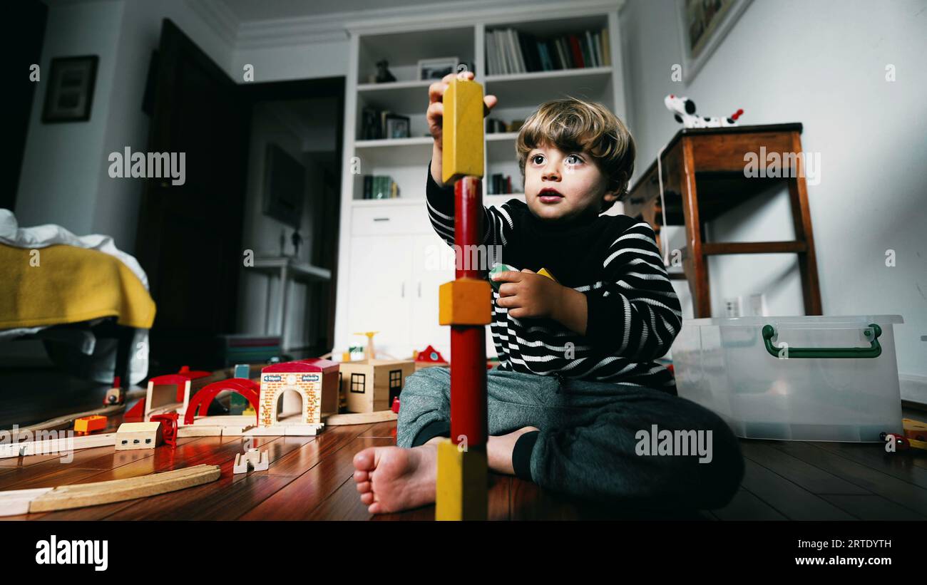 Little boy building a tower block, putting vintage blocks on top of one ...