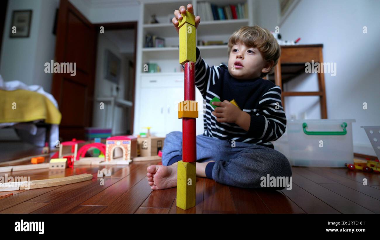 Happy child playing with tower blocks. One small boy putting vintage ...