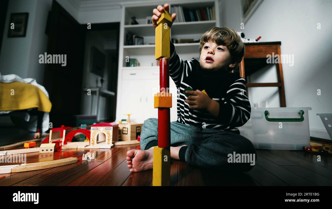 Little boy building a tower block, putting vintage blocks on top of one ...