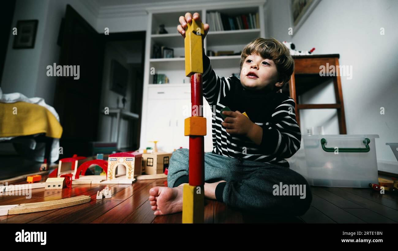 Little boy building a tower block, putting vintage blocks on top of one ...