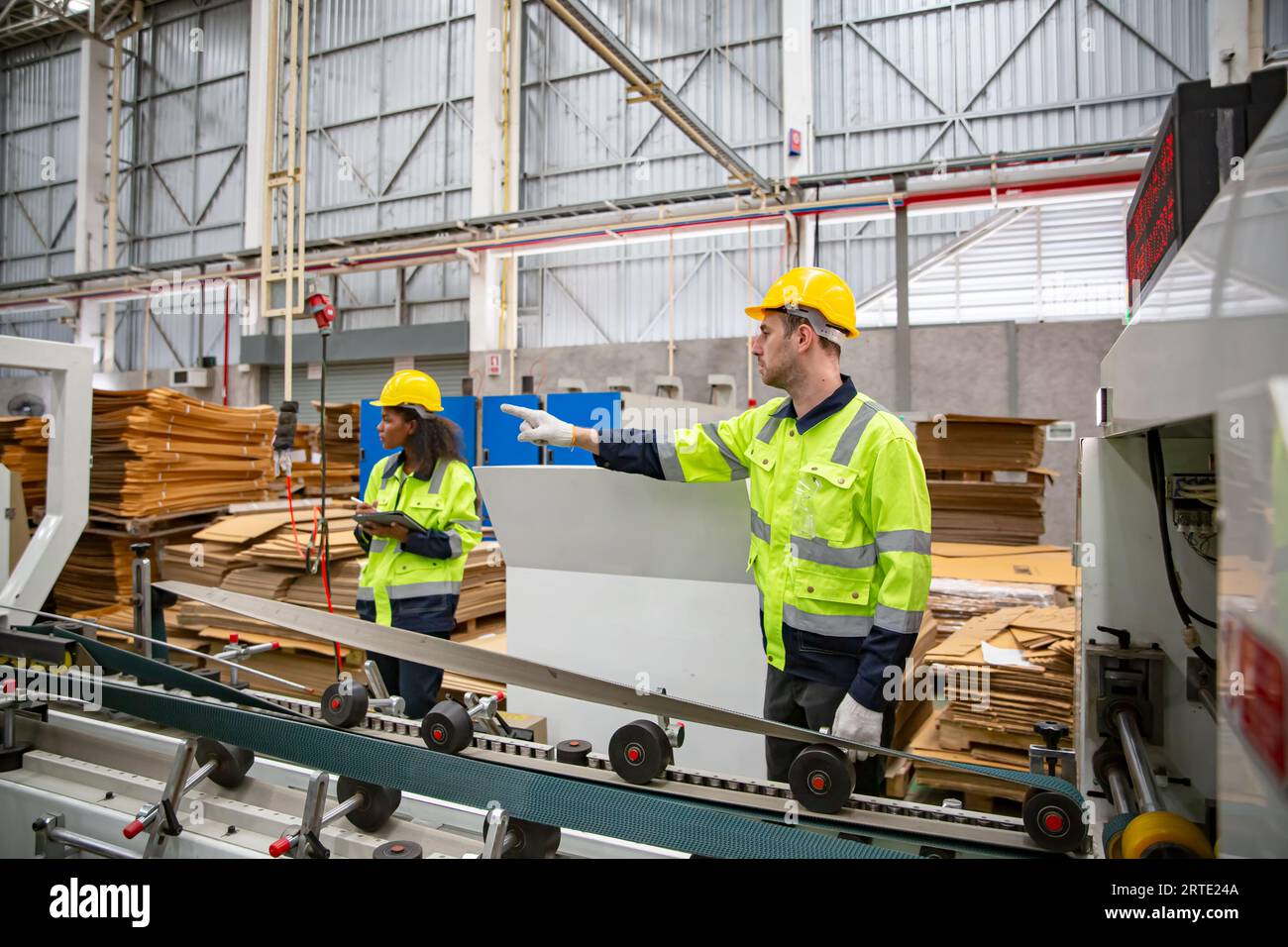 Industrial worker indoors in factory. Young technician with orange hard ...