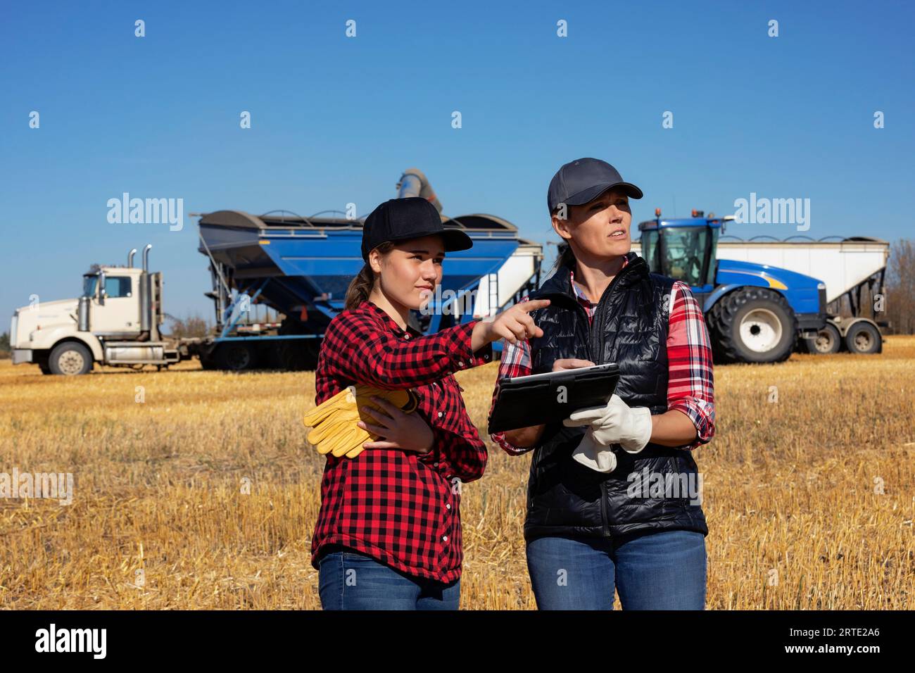 A mature farm woman standing in a field teaching her apprentice, a ...