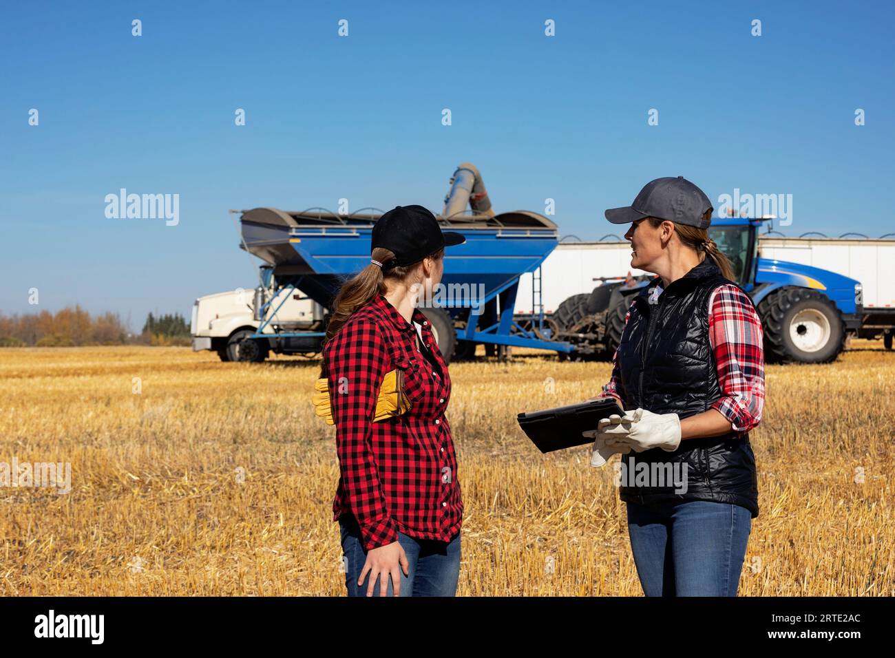 A mature farm woman standing in a field teaching her apprentice, a ...