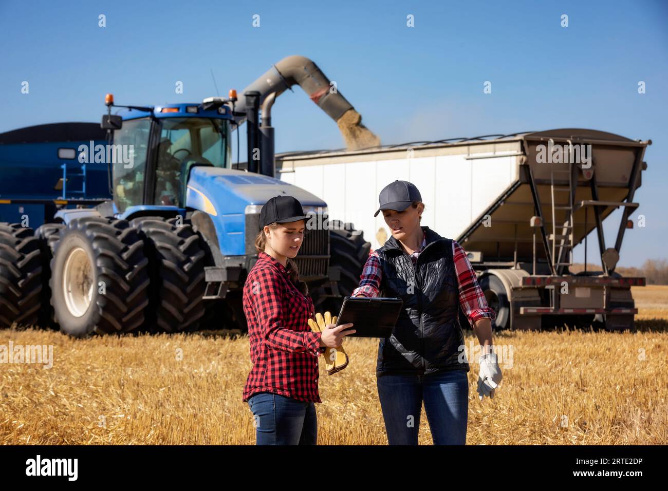 A mature farm woman standing in a field teaching her apprentice, a ...