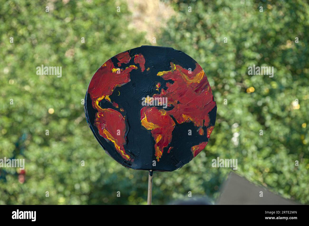 An activist holds a large placard of a red-hot dying planet earth ...