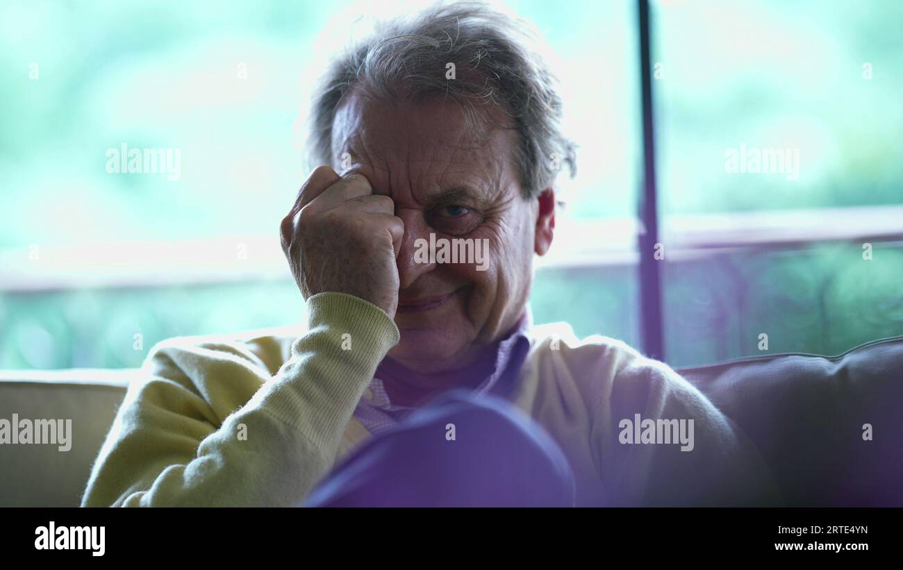 Thoughtful senior man reflecting on decision while scratching eye and ...