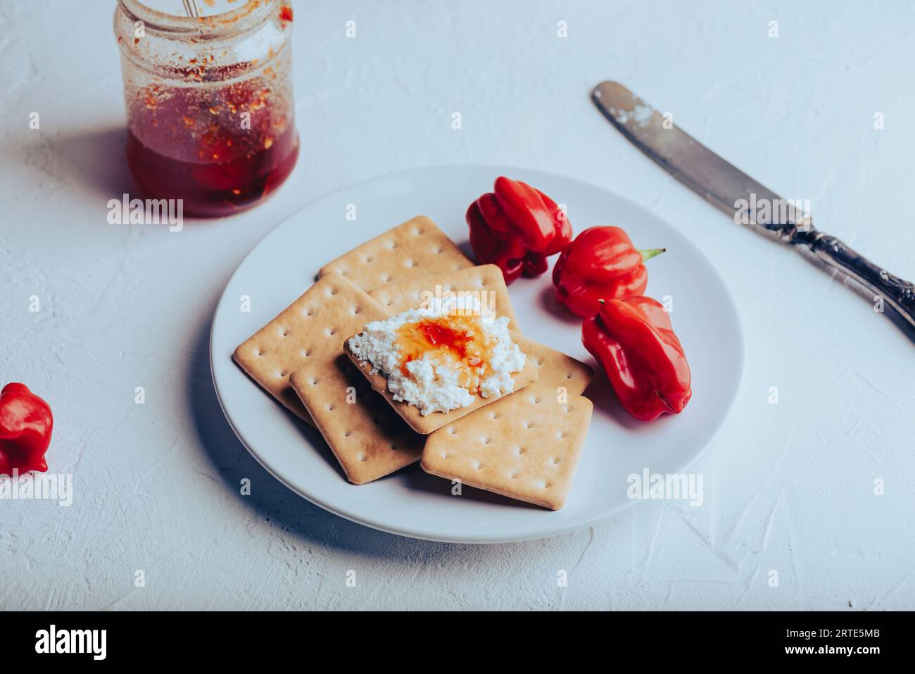 Square cracker with cream cheese and chili pepper jam Stock Photo - Alamy