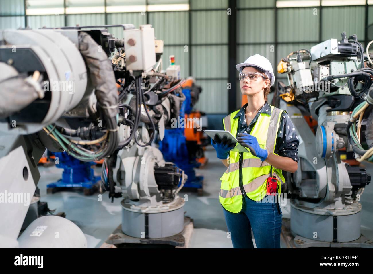 Industrial worker indoors in factory. Young technician with orange hard ...