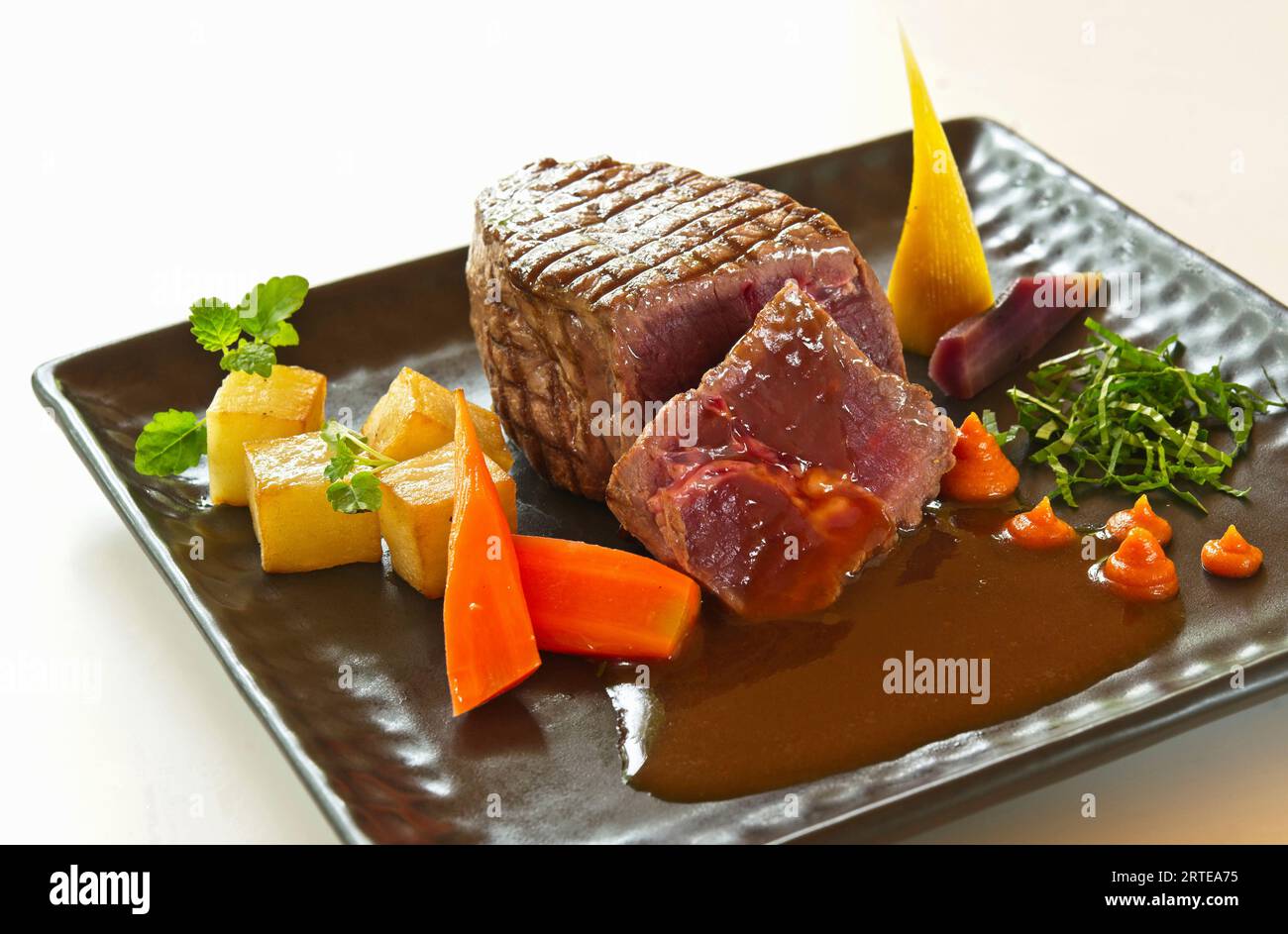 Grilled ostrich fillet with carrots and potatoes Stock Photo - Alamy